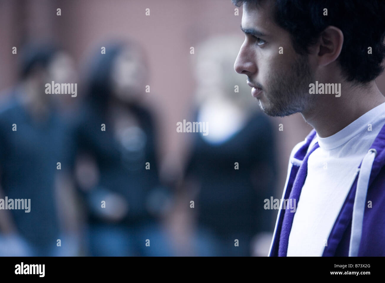 Close-up profile of serious young man, people out of focus in ...