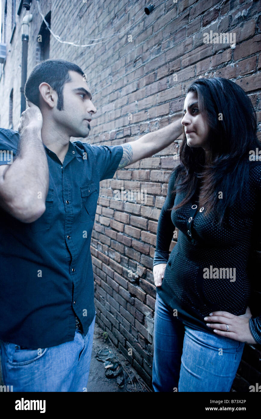 Young Hispanic couple talking outside leaning against brick wall Stock ...