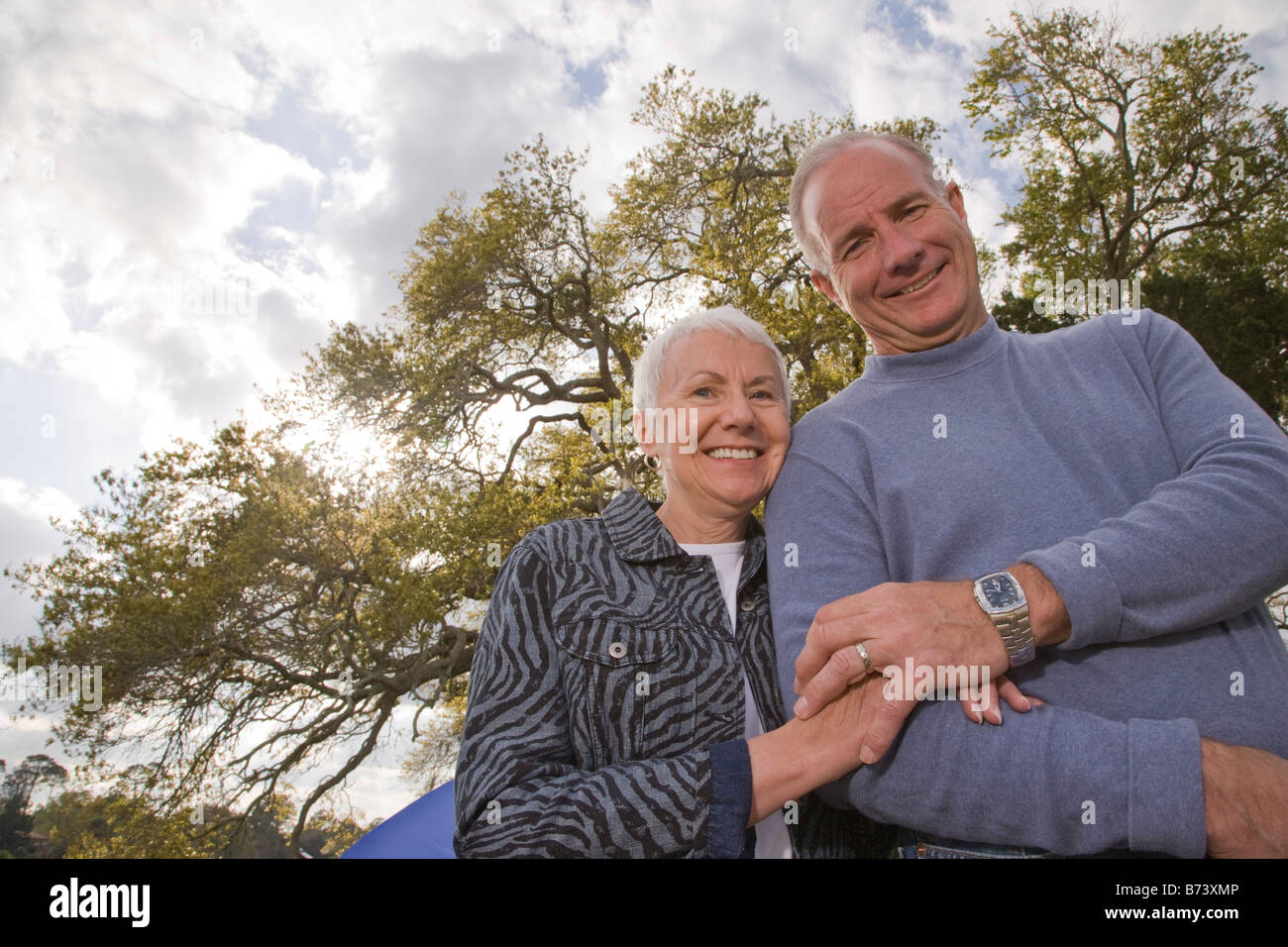 Affectionate senior couple standing arm in arm outdoors in park Stock ...