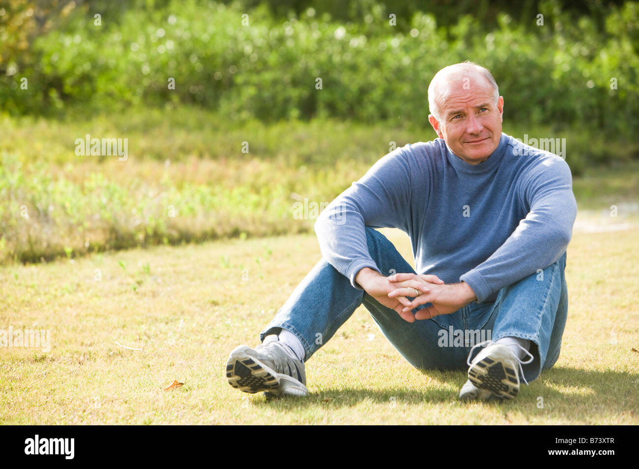 Senior man sitting on grass in park Stock Photo - Alamy