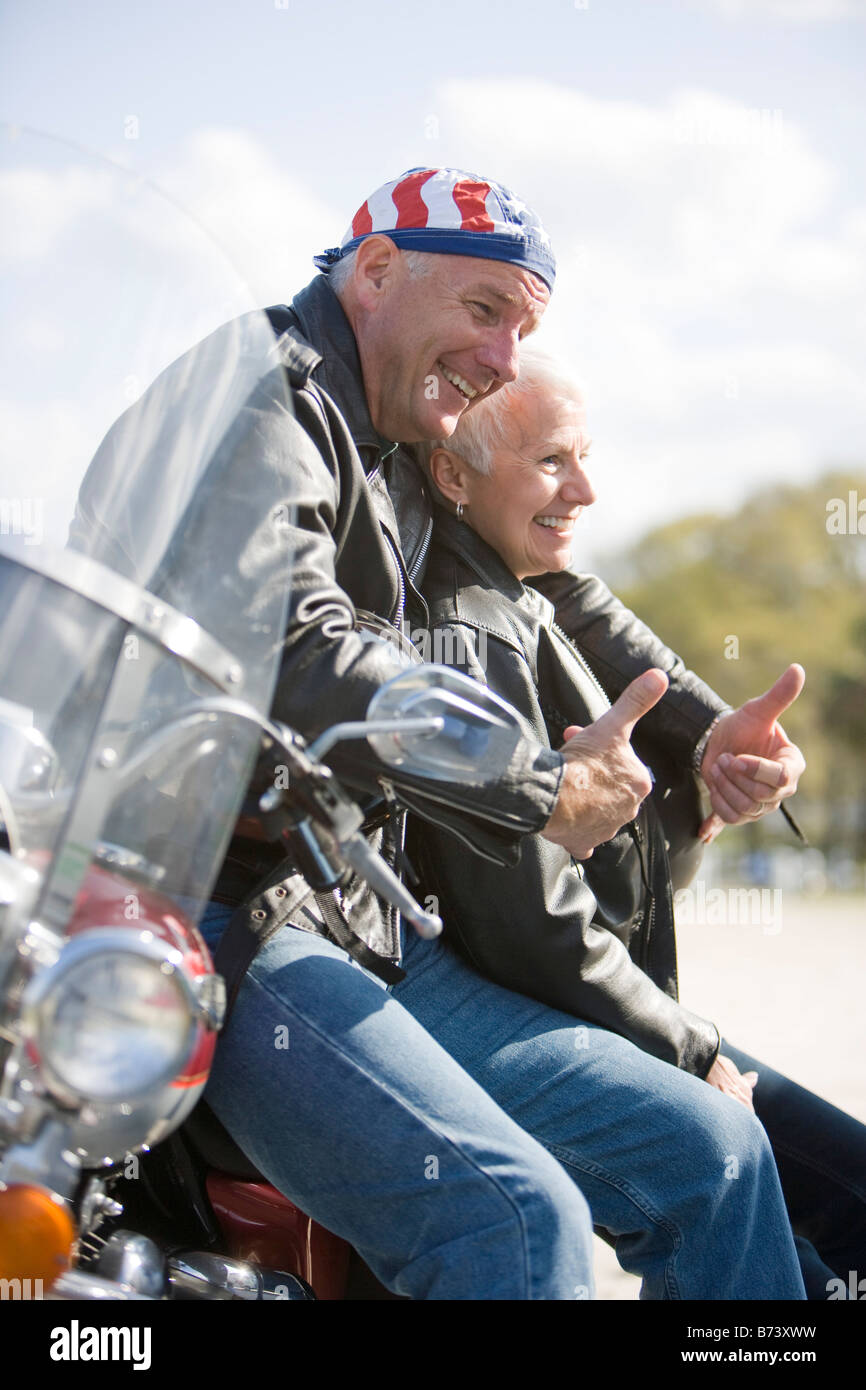 Happy senior biker couple leaning against motorcycle Stock Photo - Alamy
