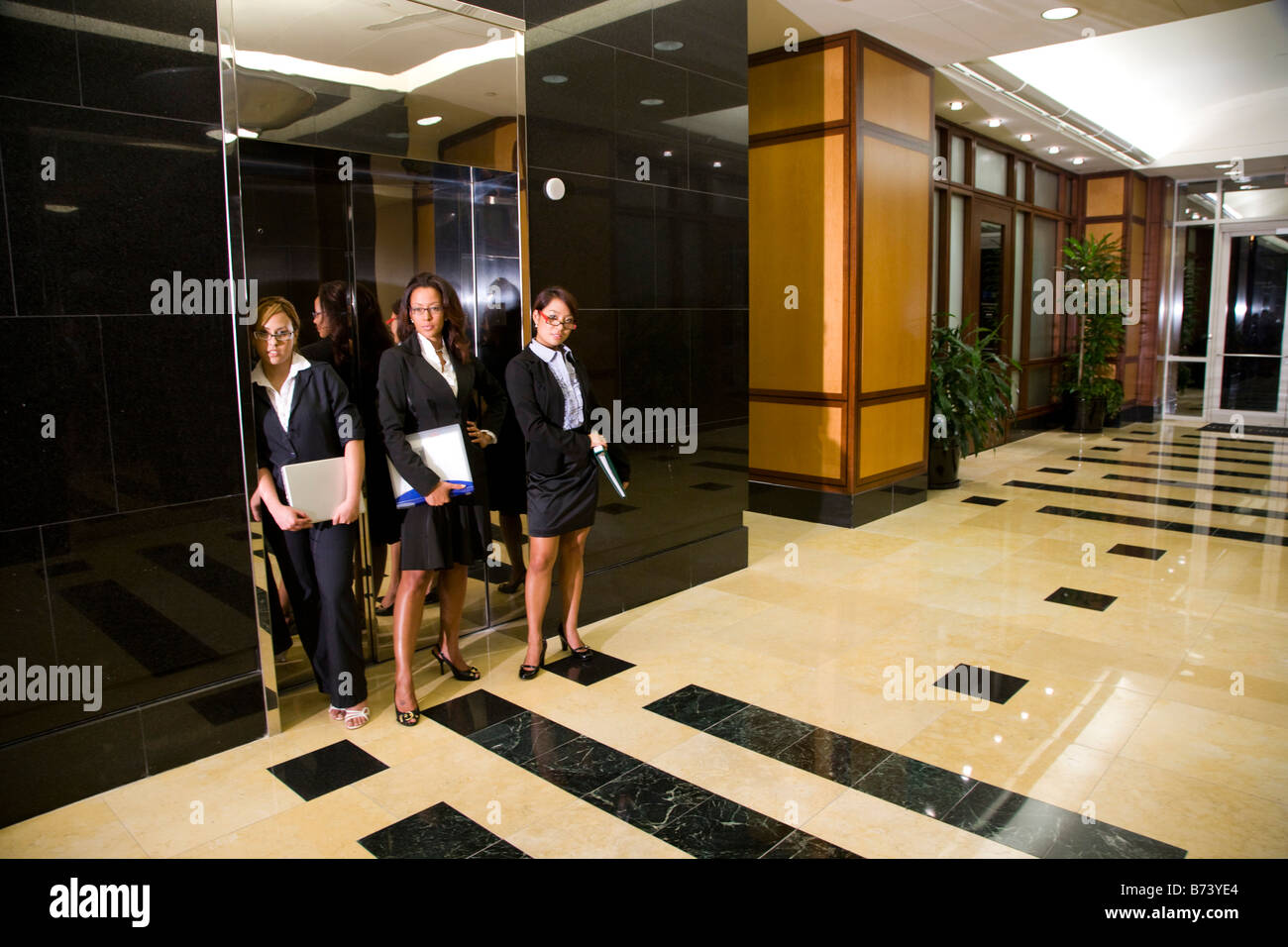 Multi-ethnic office workers waiting in office building lobby for ...