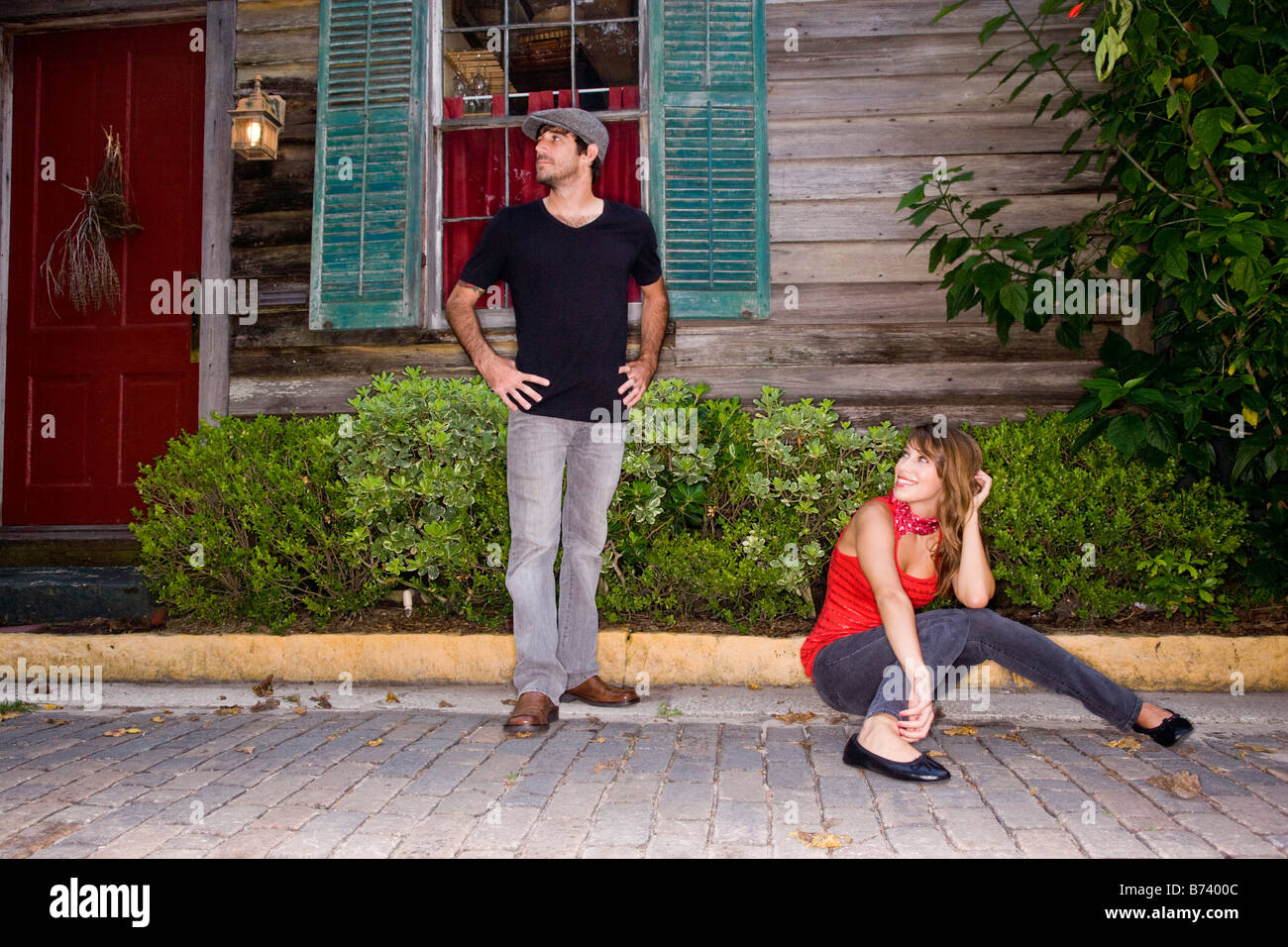 Young couple hanging out outside wooden house on cobblestone street ...