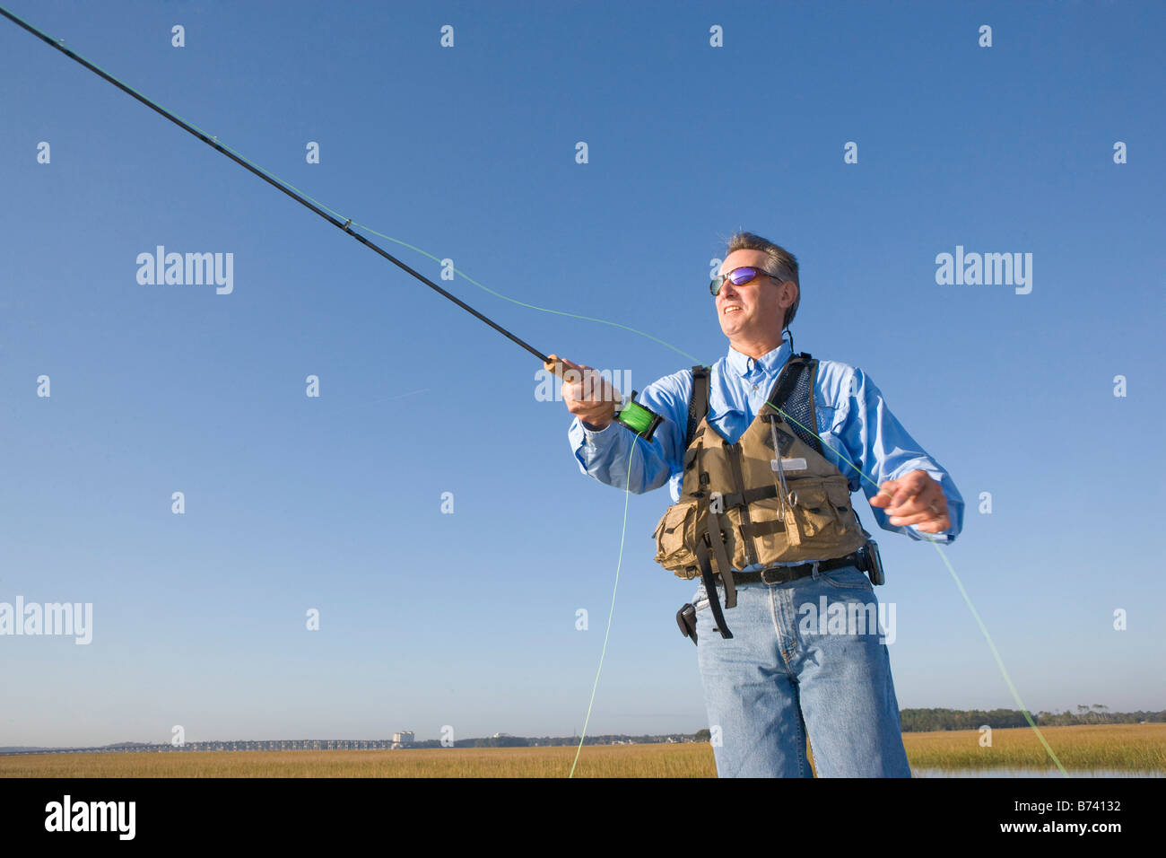 Mature adult man in sunglasses casting fishing pole in river Stock ...