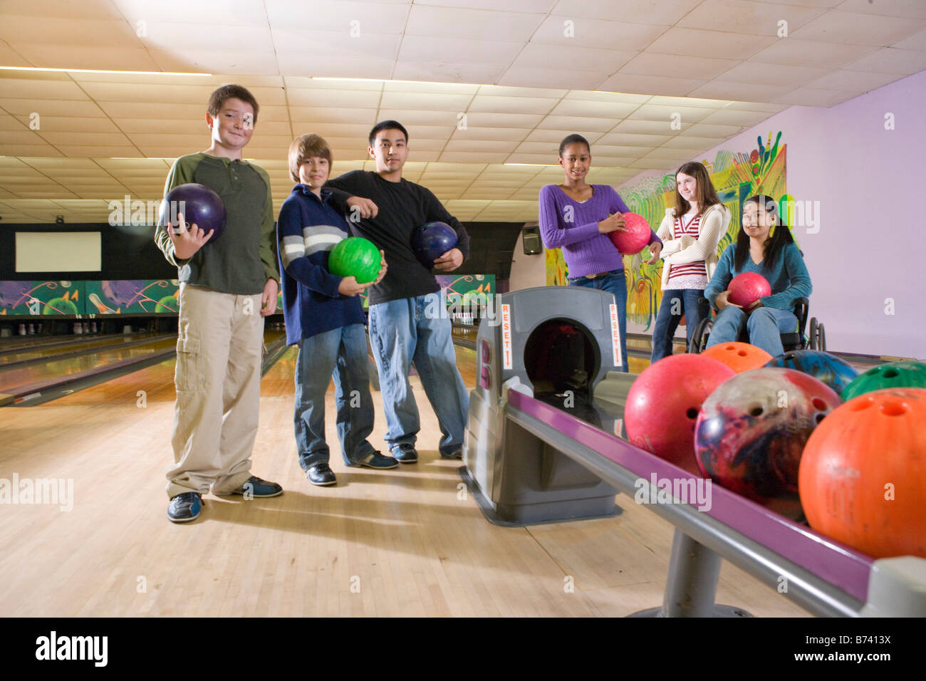 Group of multi-racial friends with girl in wheelchair at bowling alley ...