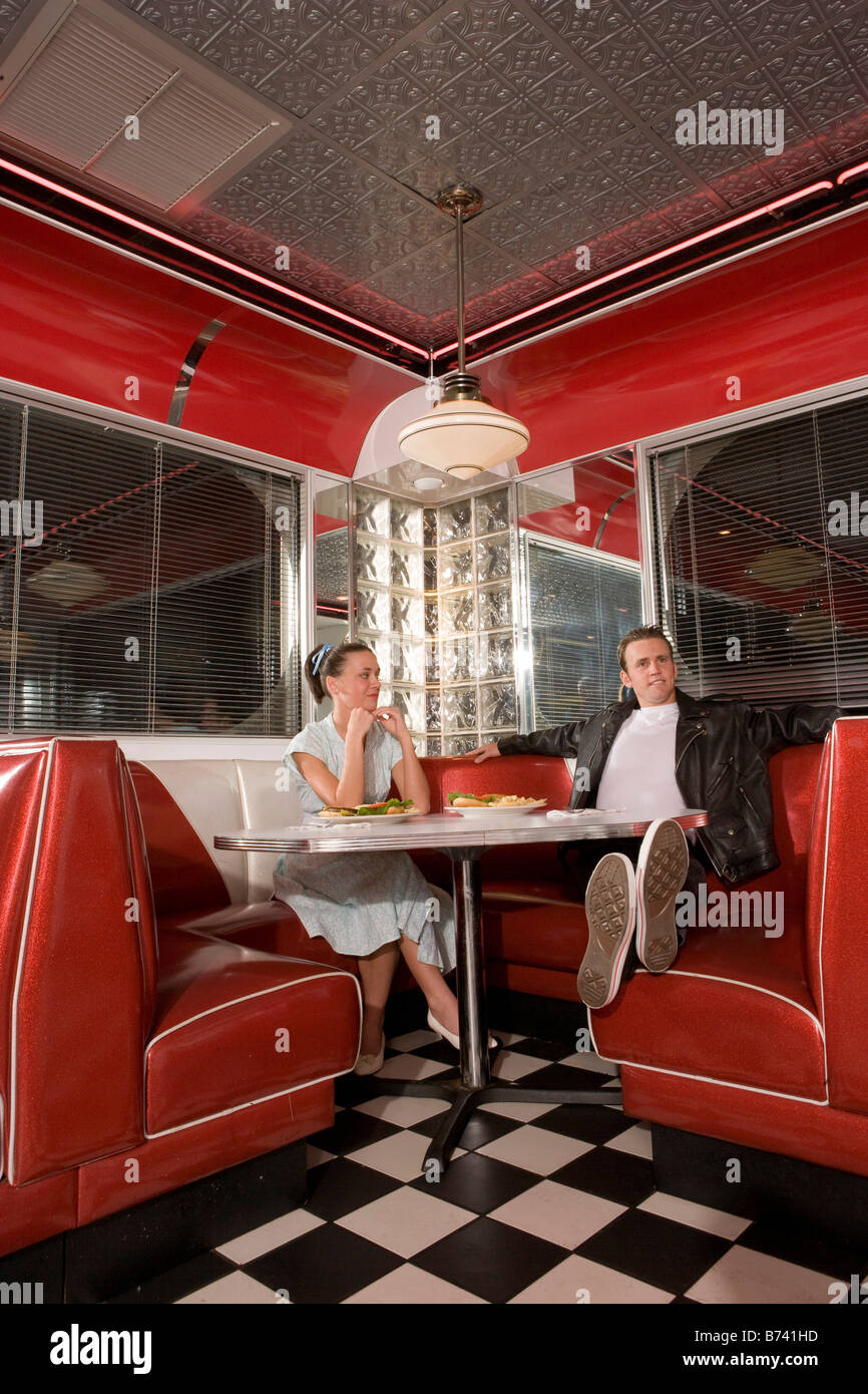 Young couple on a date in old-fashioned 50s style diner talking and ...