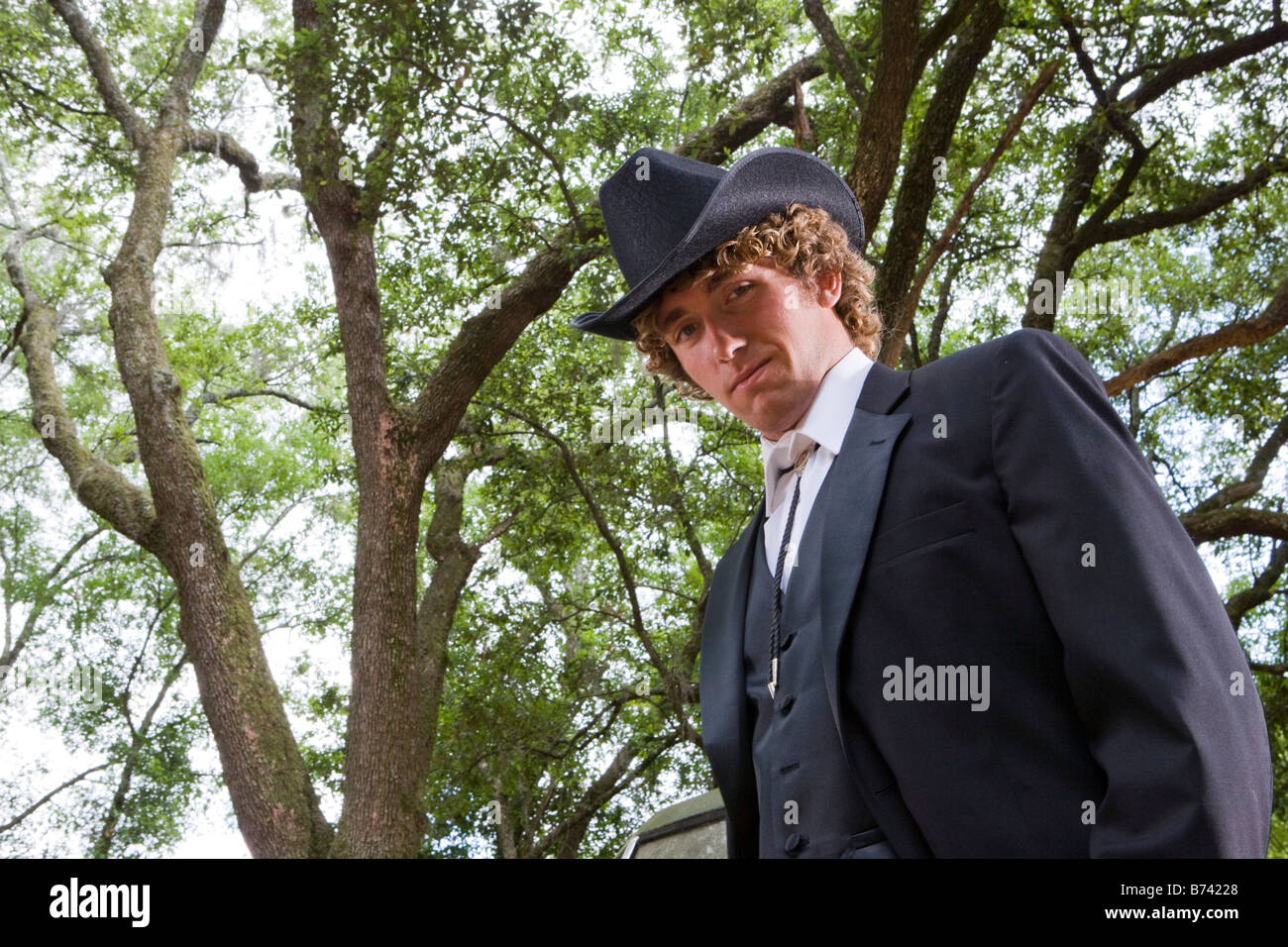 Portrait of young cowboy wearing full suit and cowboy hat outdoors ...