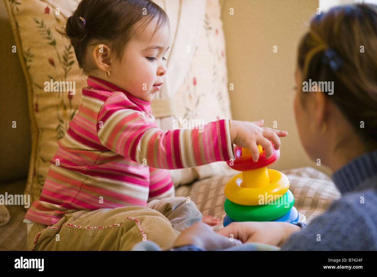 Hispanic mother watching daughter stack plastic rings Stock Photo - Alamy