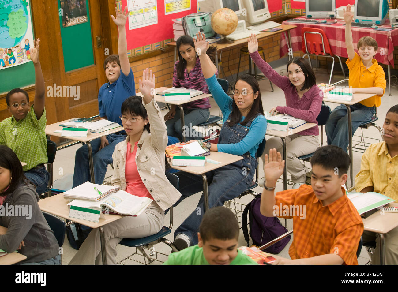 Students raising hands in classroom Stock Photo - Alamy