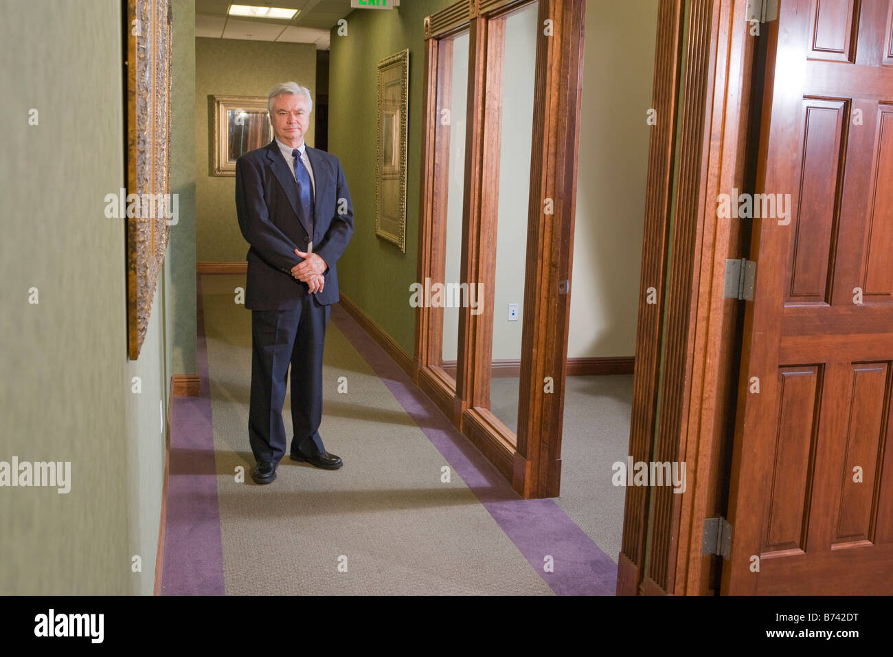 Portrait of experienced businessman standing in office corridor Stock ...