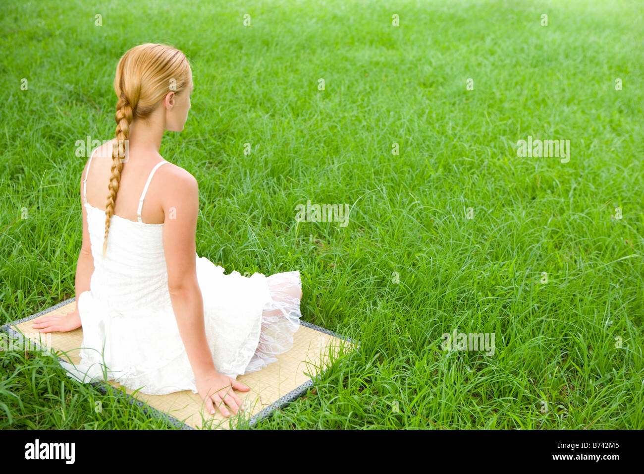 Young woman sitting on exercise mat Stock Photo - Alamy