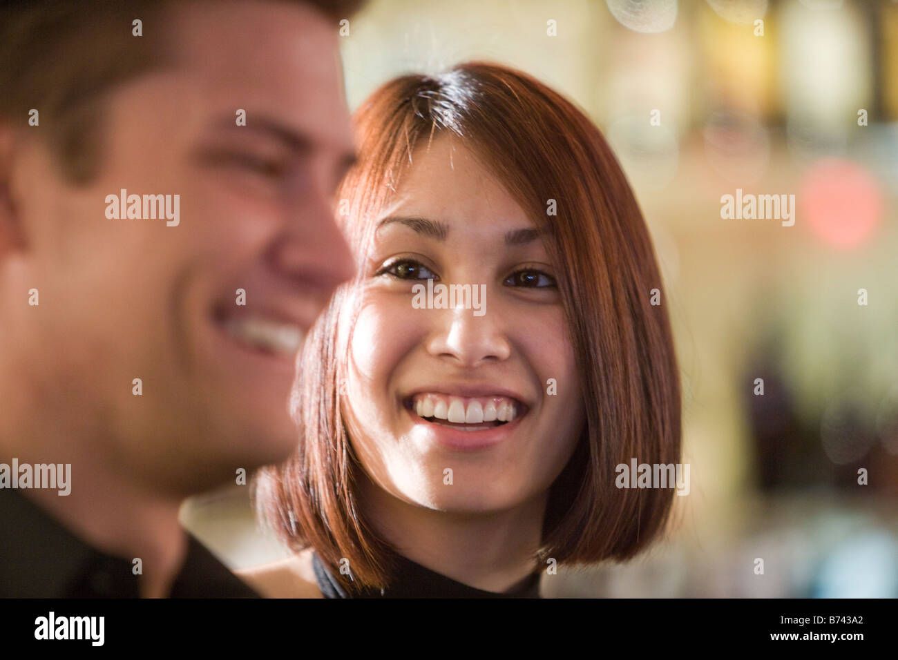Face of pretty young woman smiling with boyfriend in foreground Stock ...