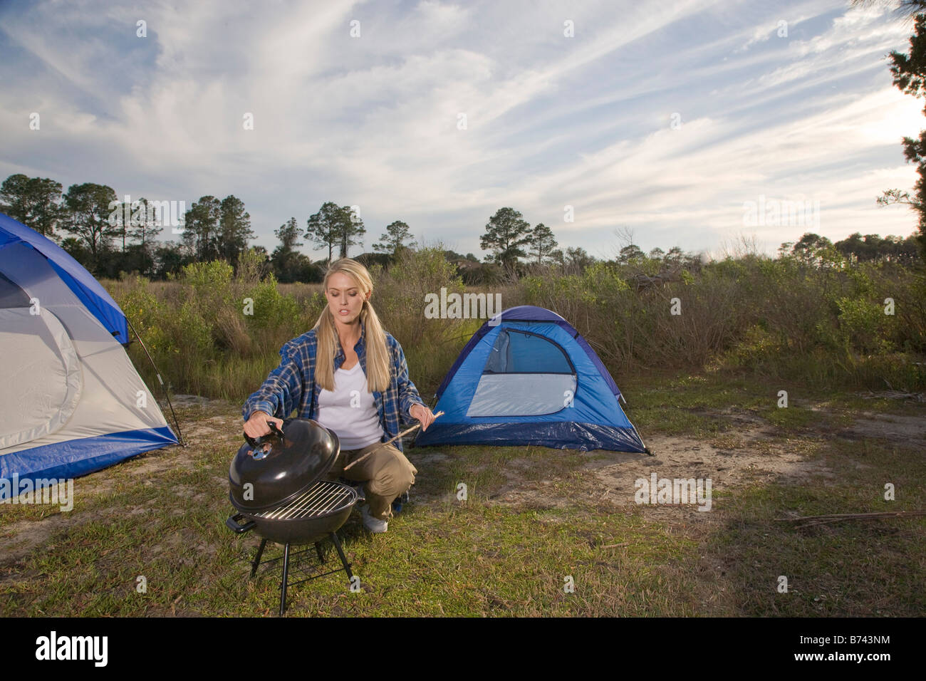 Woman preparing food on barbecue at campsite in park Stock Photo - Alamy