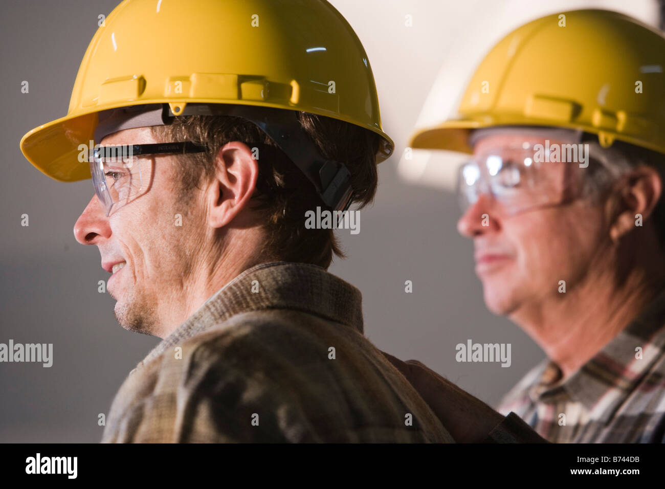 Side view of two male construction workers wearing hard hats Stock ...