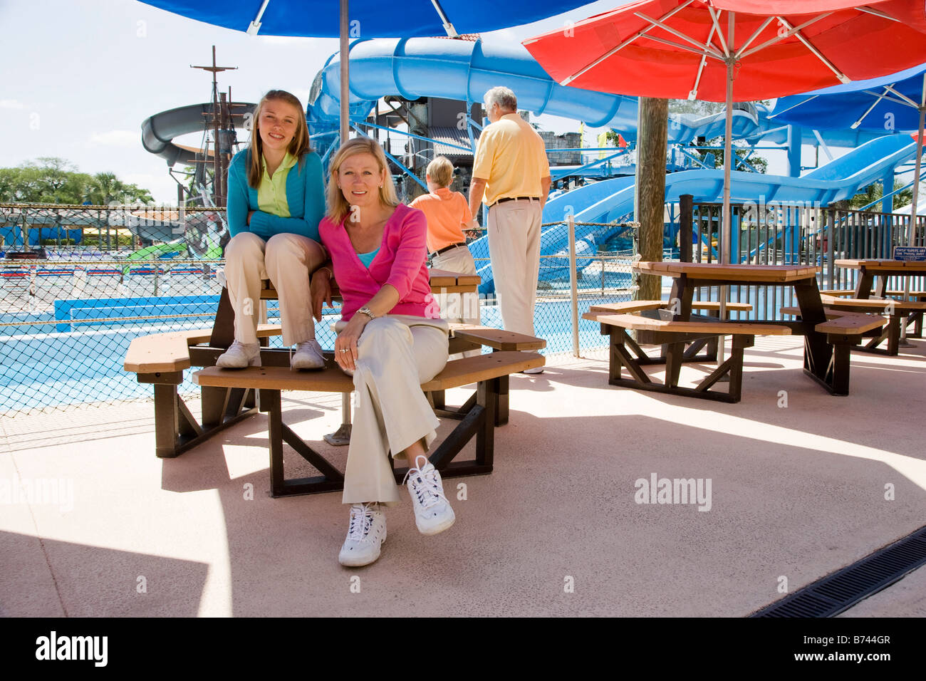 Family at relaxing at picnic tables on outing at water park Stock Photo ...
