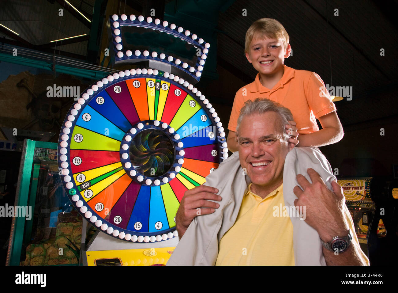 Father and son posing in front of an arcade game at an amusement park ...