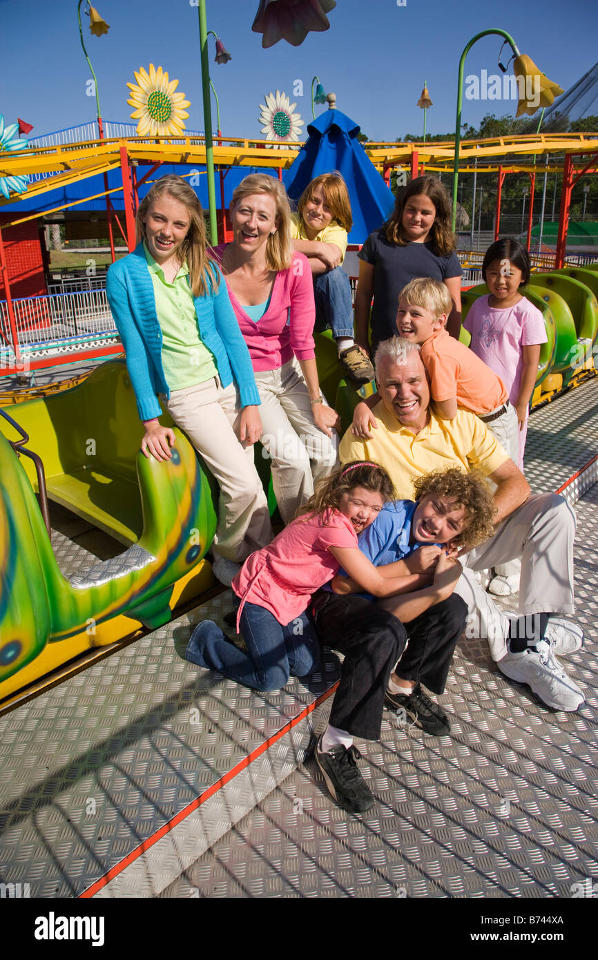 Group of family and friends in front of roller coaster at amusement ...