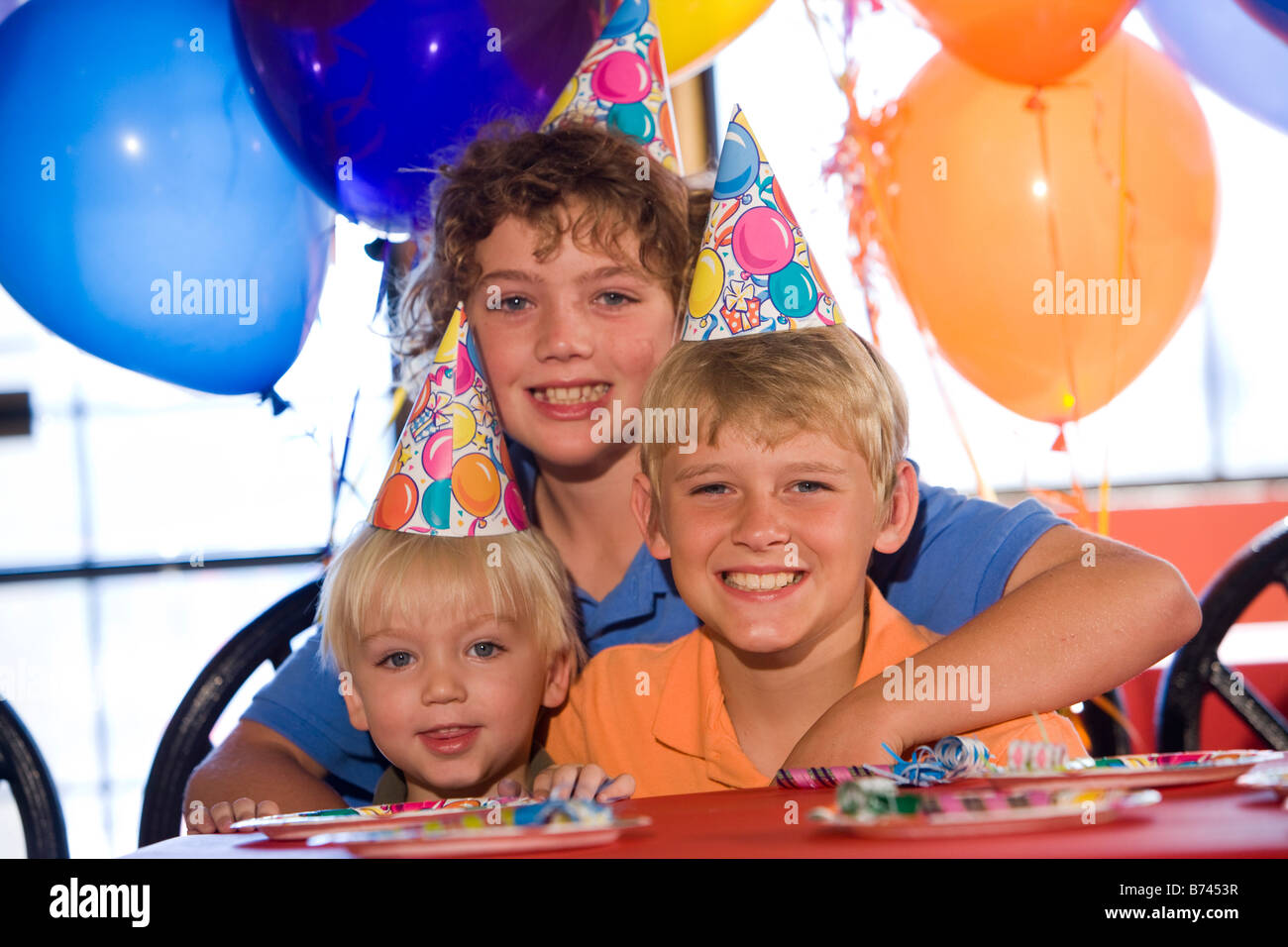 Three brothers posing at kids birthday party with lots of balloons ...
