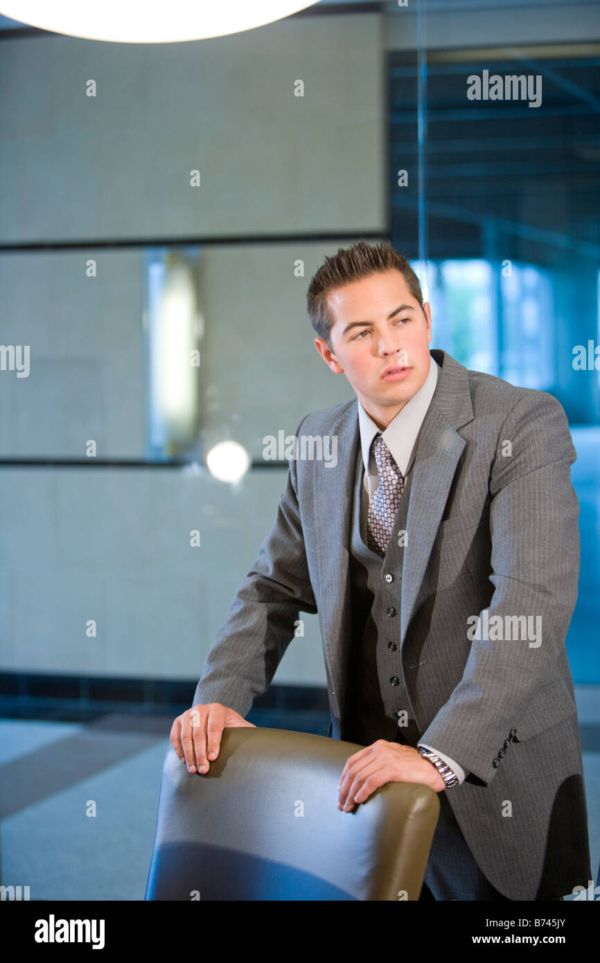 Young businessman leaning on empty office chair Stock Photo - Alamy