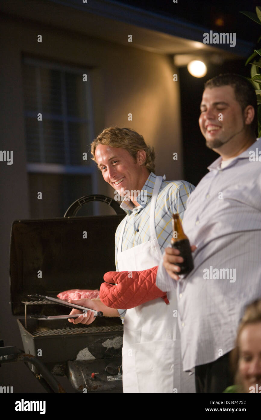 Two friends cooking barbeque in backyard at night Stock Photo - Alamy