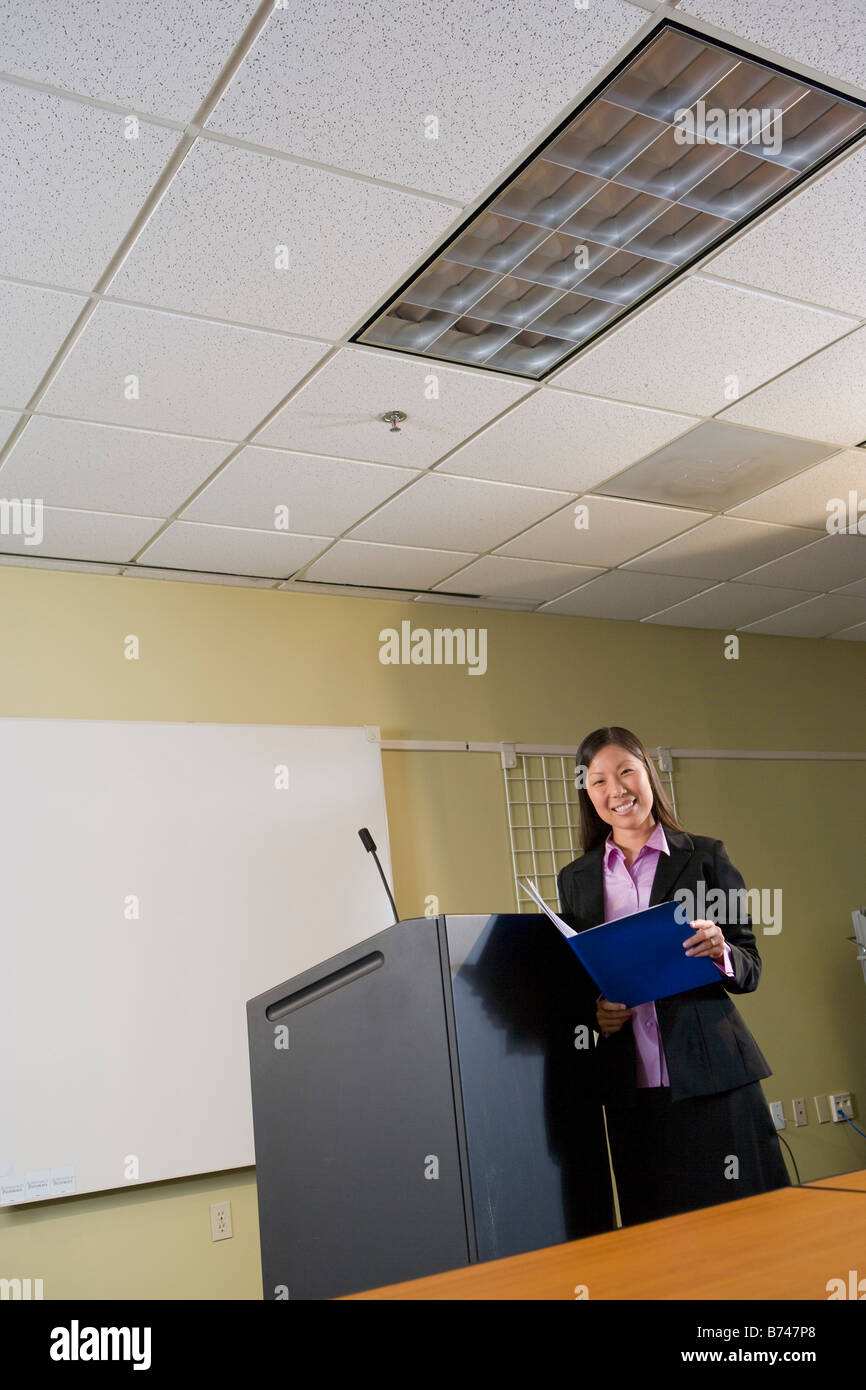 Young Asian woman reading file by lectern in board room Stock Photo - Alamy