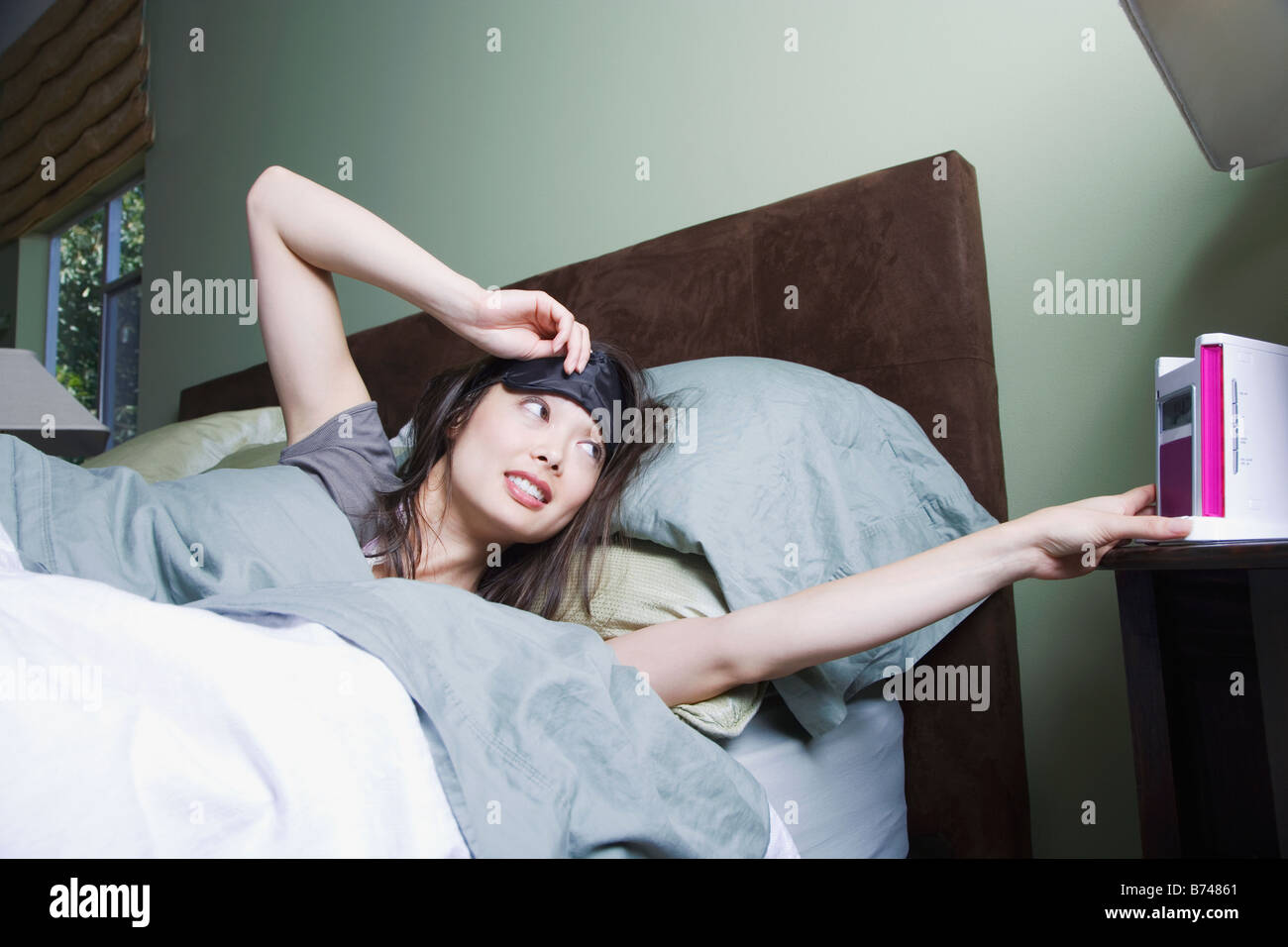 Woman waking to alarm clock Stock Photo - Alamy