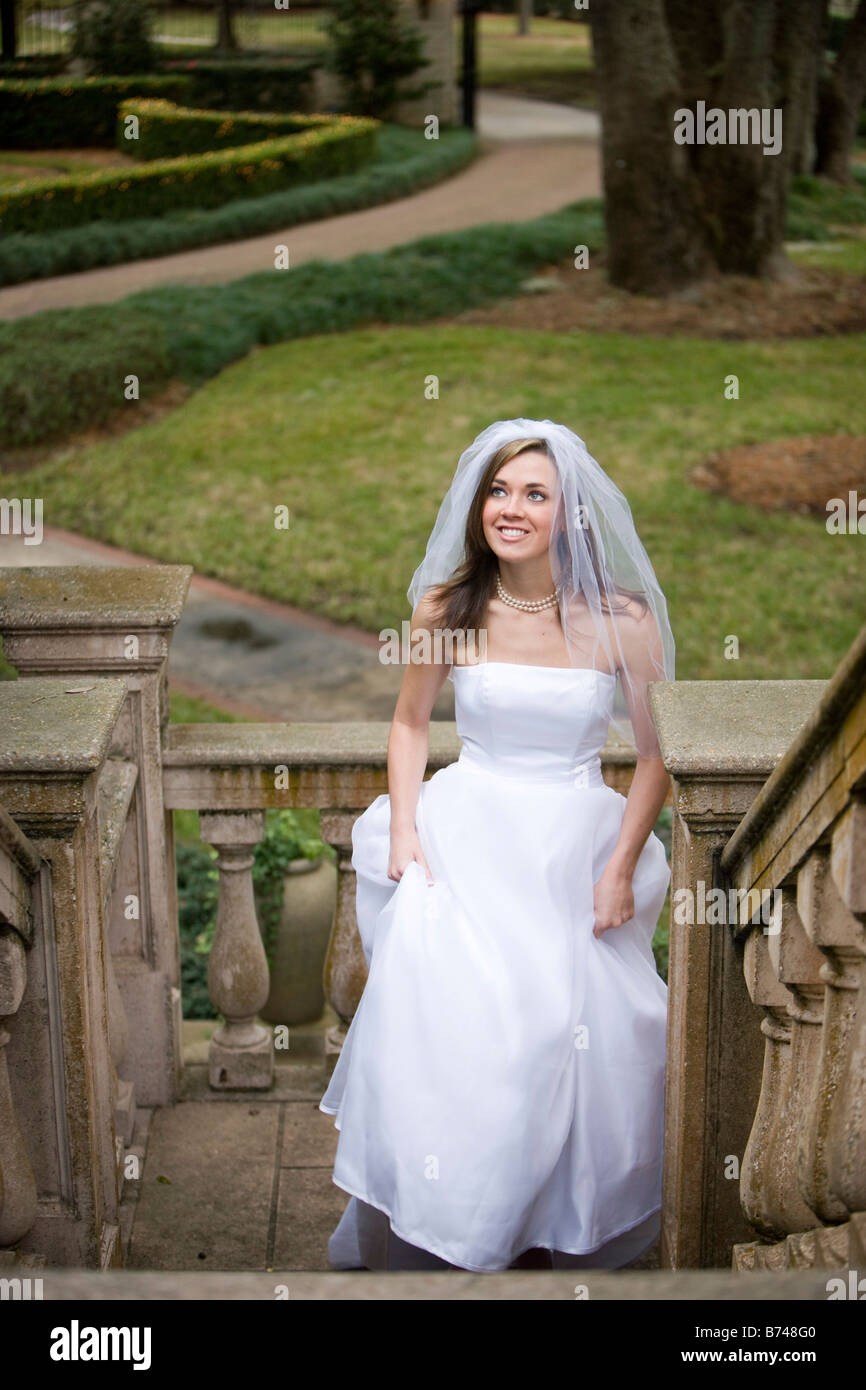 Happy young bride in wedding dress walking up stairs outdoors Stock ...