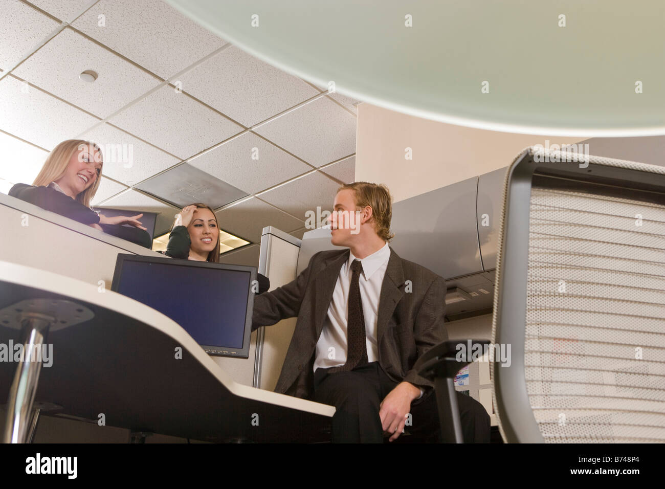 Office workers chatting at cubicle desk Stock Photo - Alamy