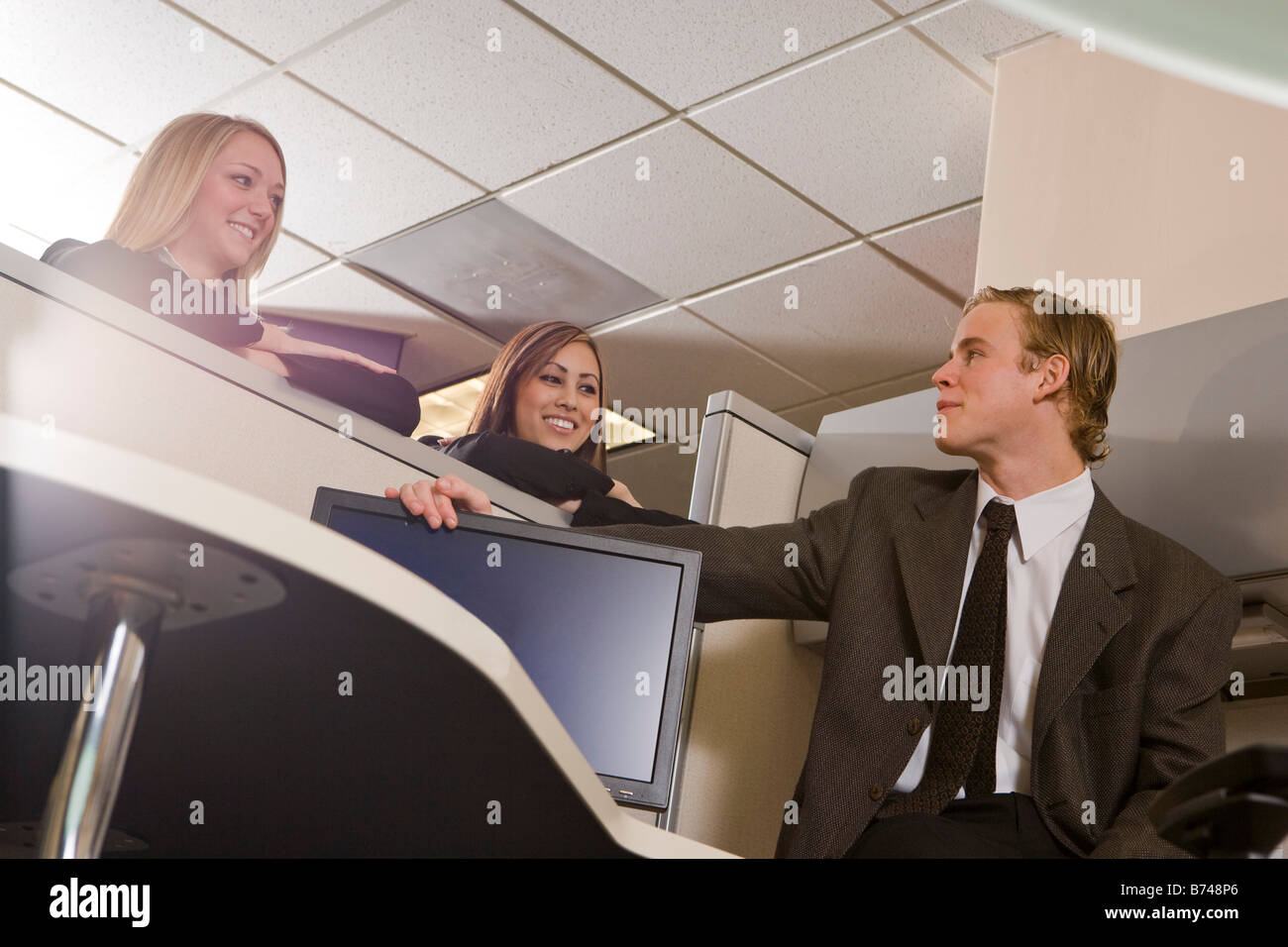 Office workers chatting at cubicle desk Stock Photo - Alamy