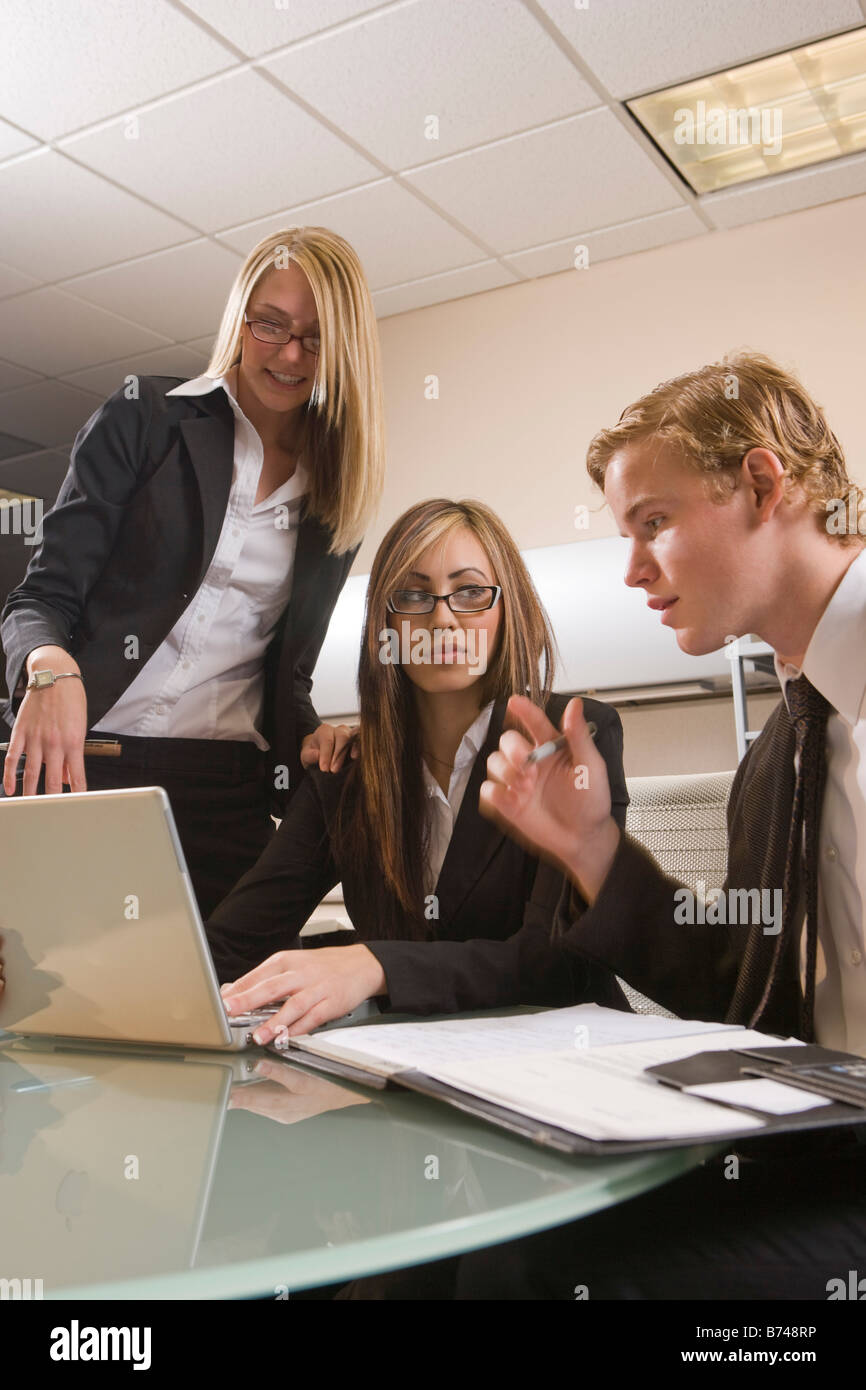 Three young office workers working together on laptop at desk Stock Photo - Alamy