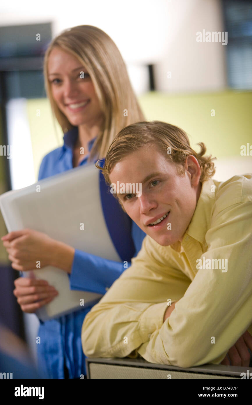 Two young office workers smiling, focus on man Stock Photo - Alamy
