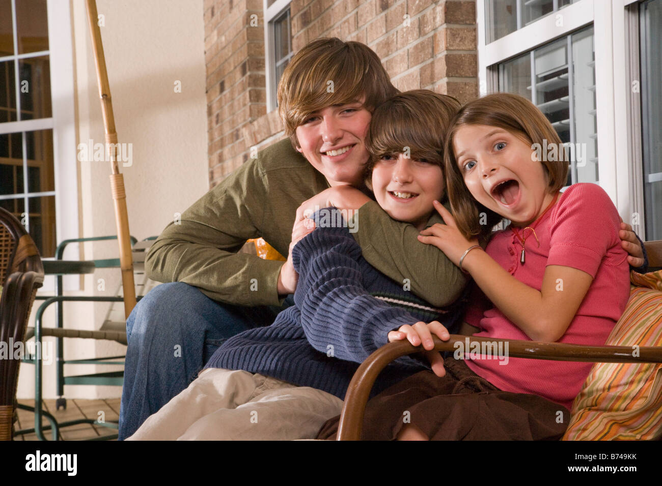 Siblings hugging each other on porch Stock Photo - Alamy