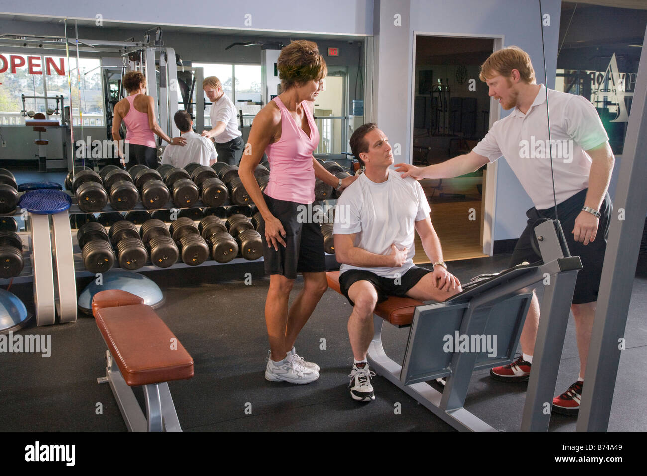 Middle-aged couple in session with personal trainer at gym Stock Photo ...