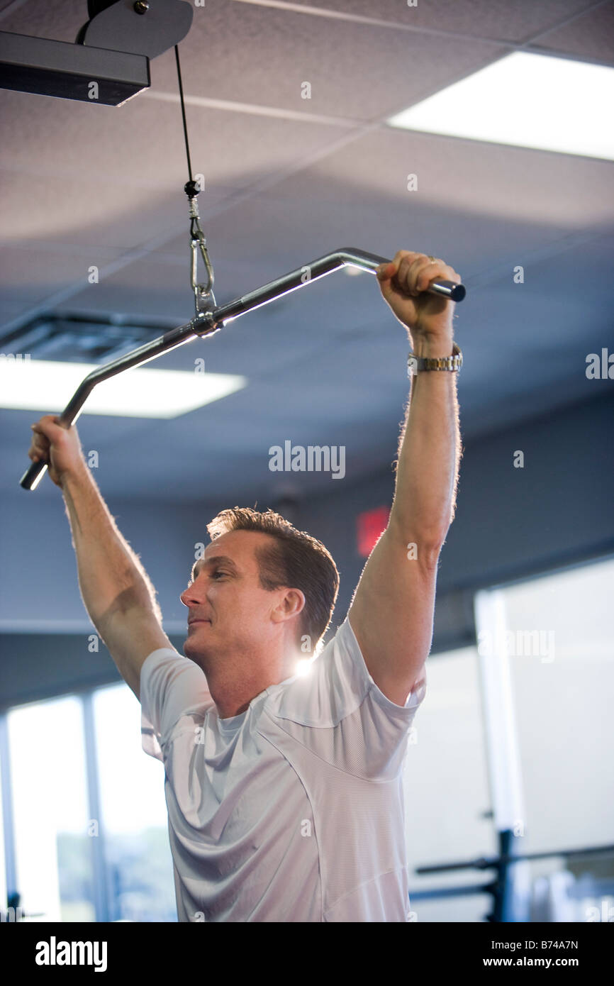 Middle-aged man pulling weight machine at gym Stock Photo - Alamy