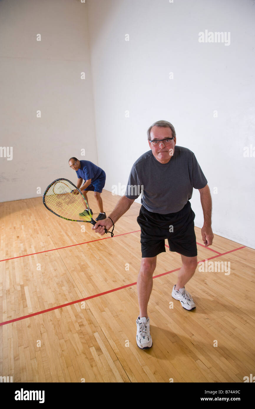Multi-ethnic senior men playing racketball at indoor court Stock Photo ...