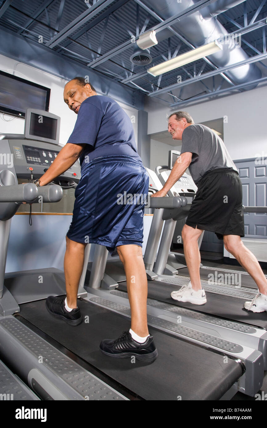 Multi-ethnic senior men walking on treadmill at health gym Stock Photo ...