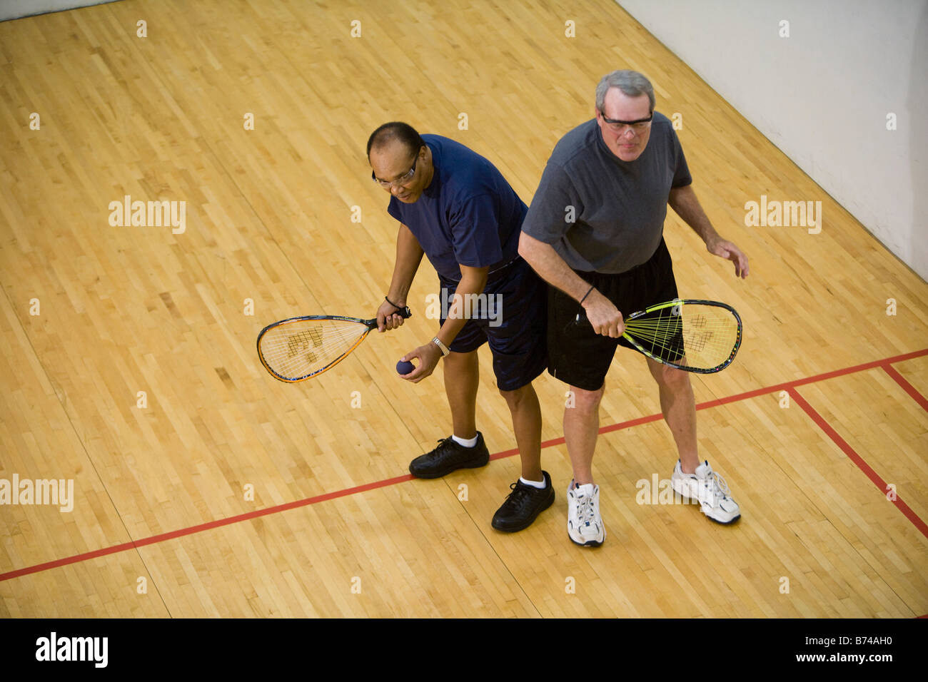 Multi-ethnic senior men playing racketball at indoor court Stock Photo ...
