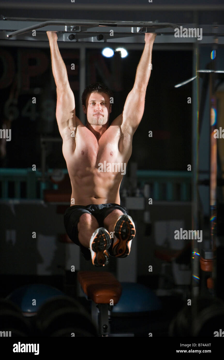 Physically fit young man working out in fitness center Stock Photo - Alamy
