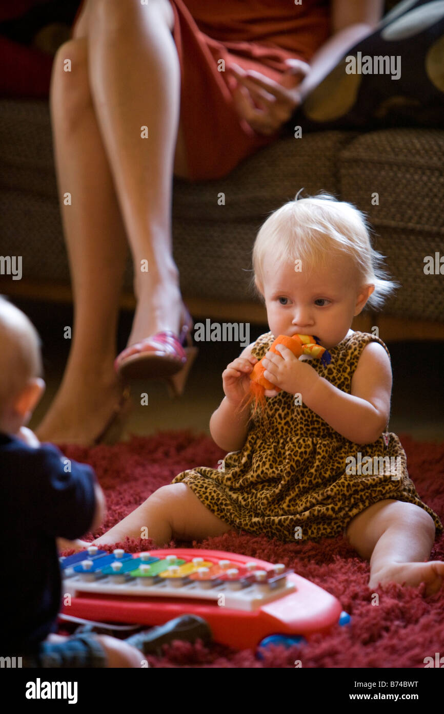 Baby sitting on rug playing Stock Photo - Alamy