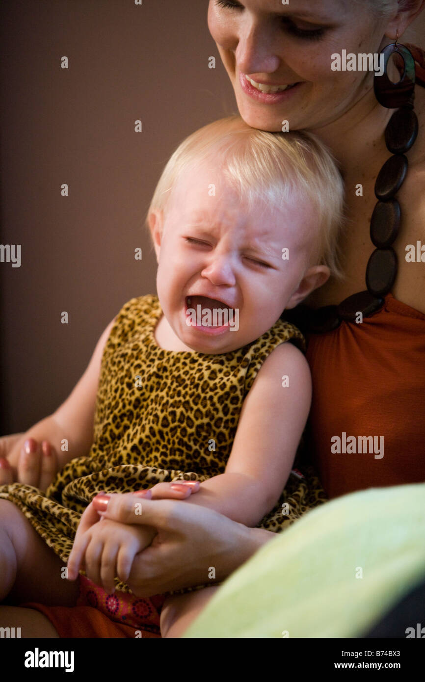 Baby girl crying while sitting on mother's lap Stock Photo - Alamy