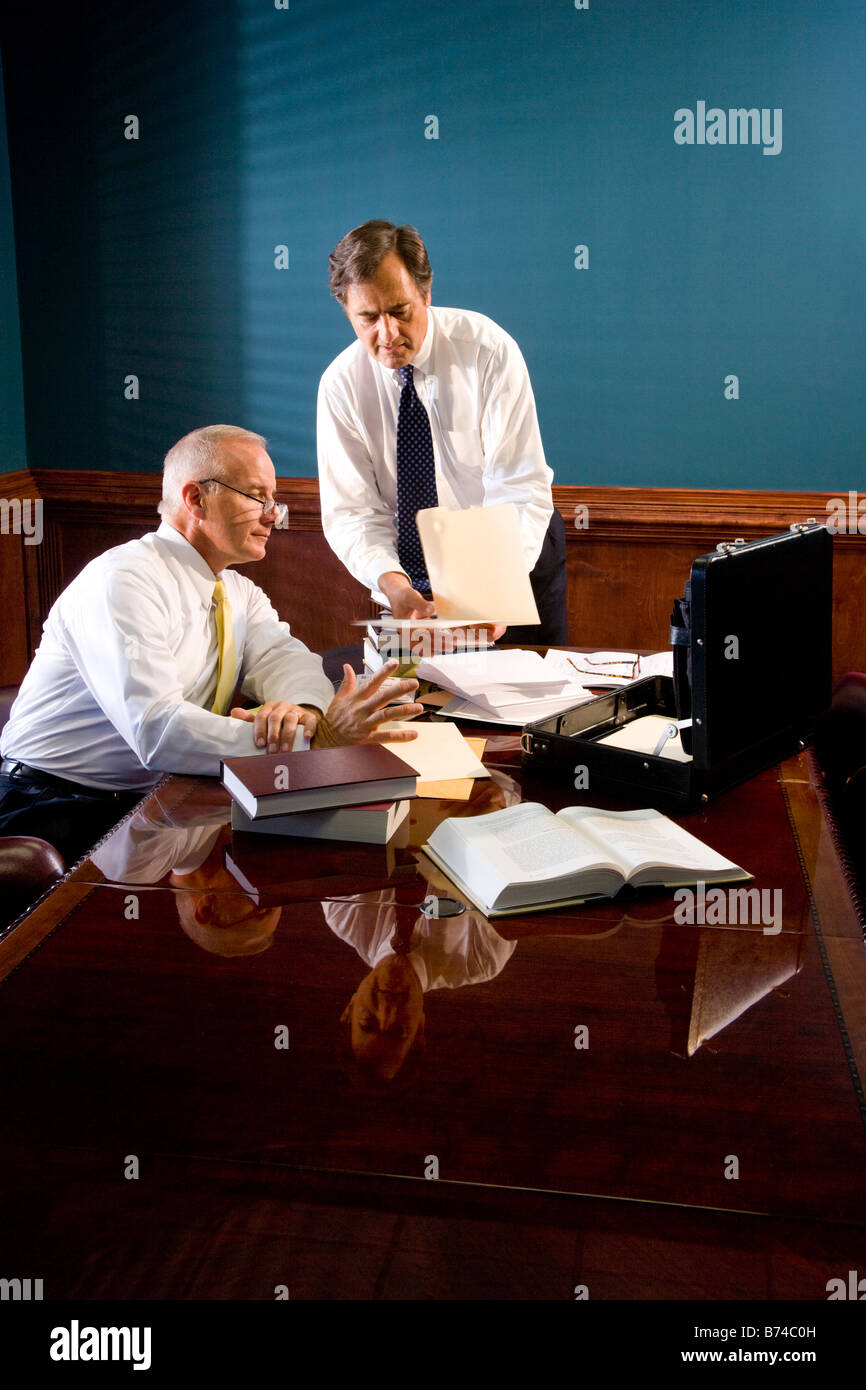 Businessmen in conference room researching information in books Stock ...