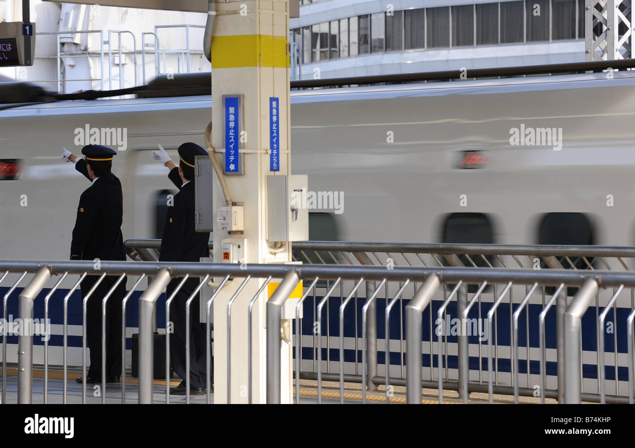 Train guards on the platform of Tokyo Railway Station as a Shinkansen ...