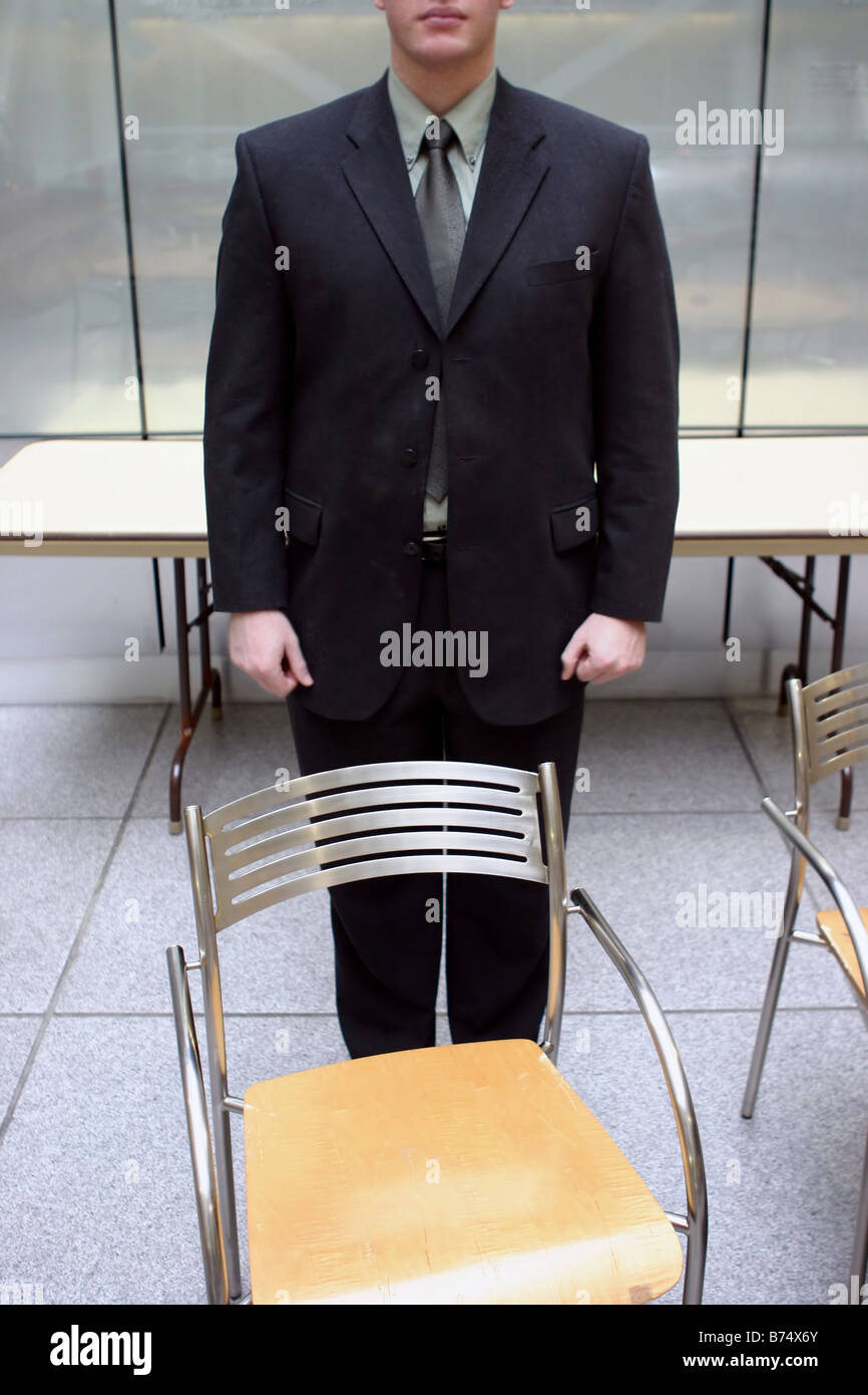 Businessman dressed in full suit standing behind empty office chair ...