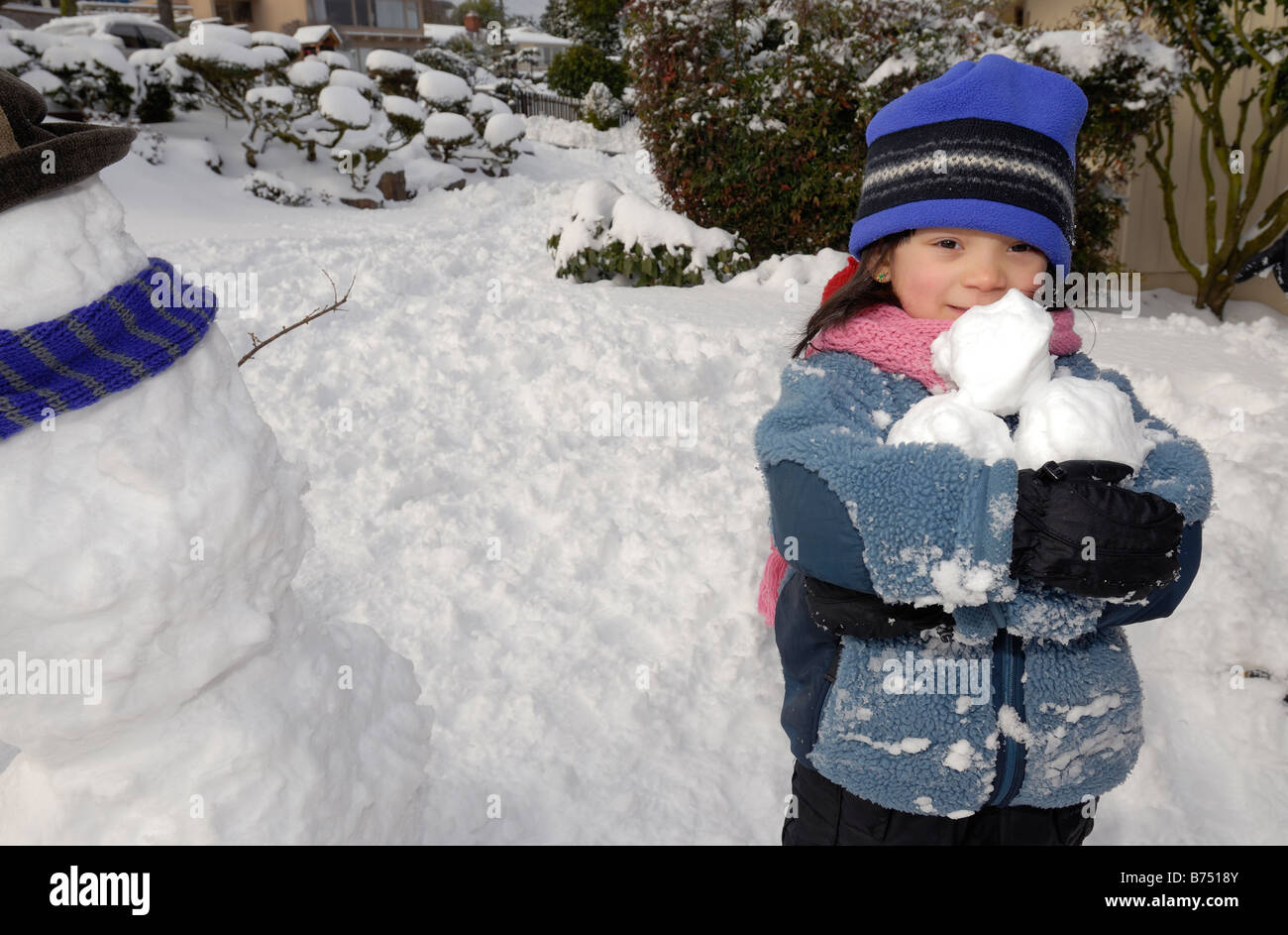 4 year old girl holding three snowballs Stock Photo - Alamy