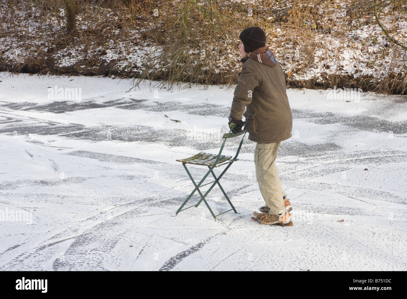 Girl learning to ice skate behind a chair Stock Photo - Alamy