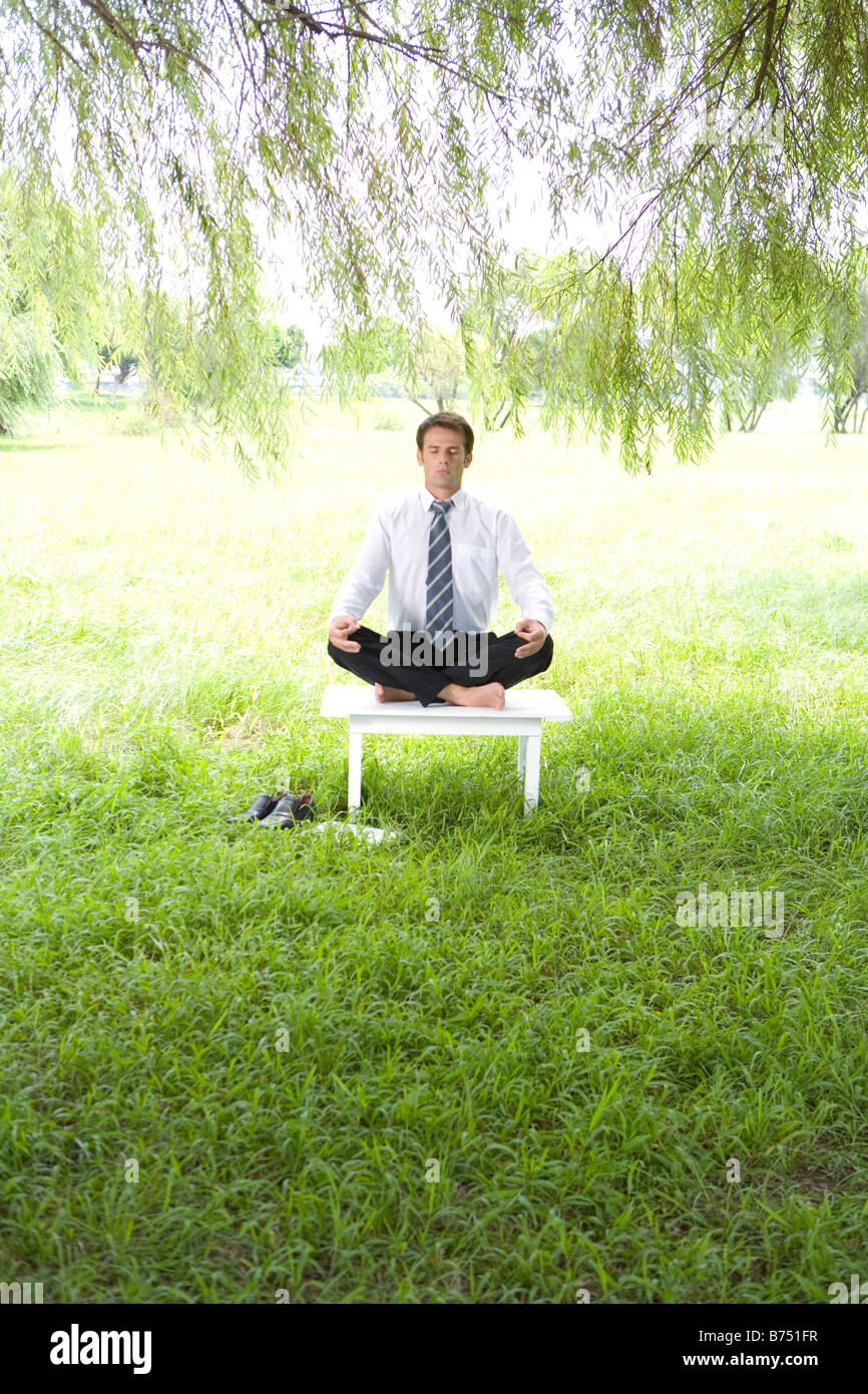 One mid adult man in lotus position sitting on desk outdoors Stock ...