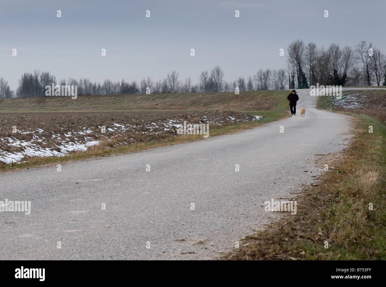 a man walks on a rural road in winter Stock Photo - Alamy