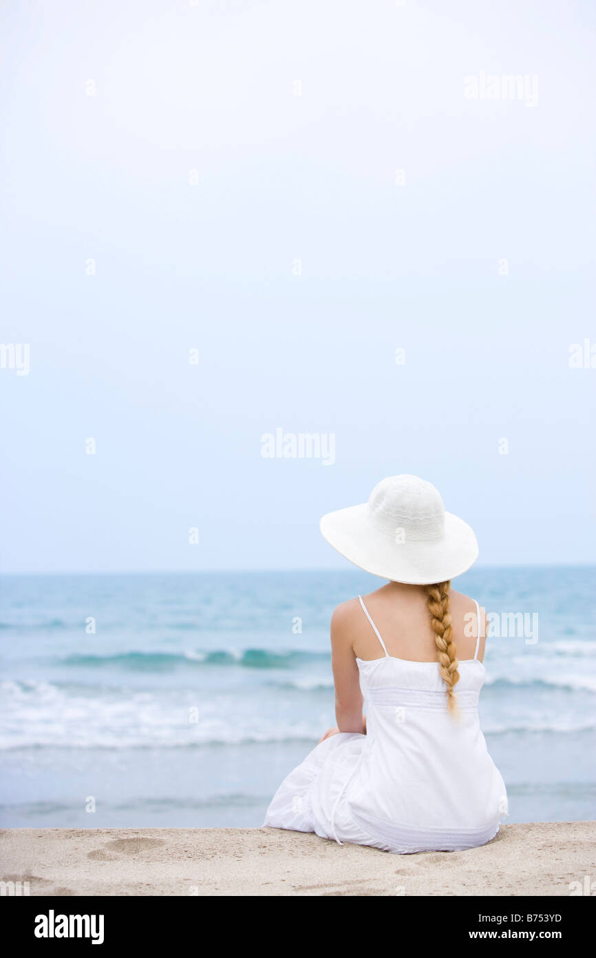 Young woman sitting on beach rear view Stock Photo - Alamy