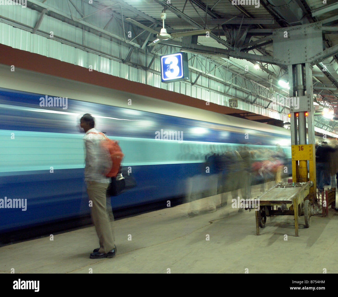 indian commuter rail passenger at a delhi station with passing train ...