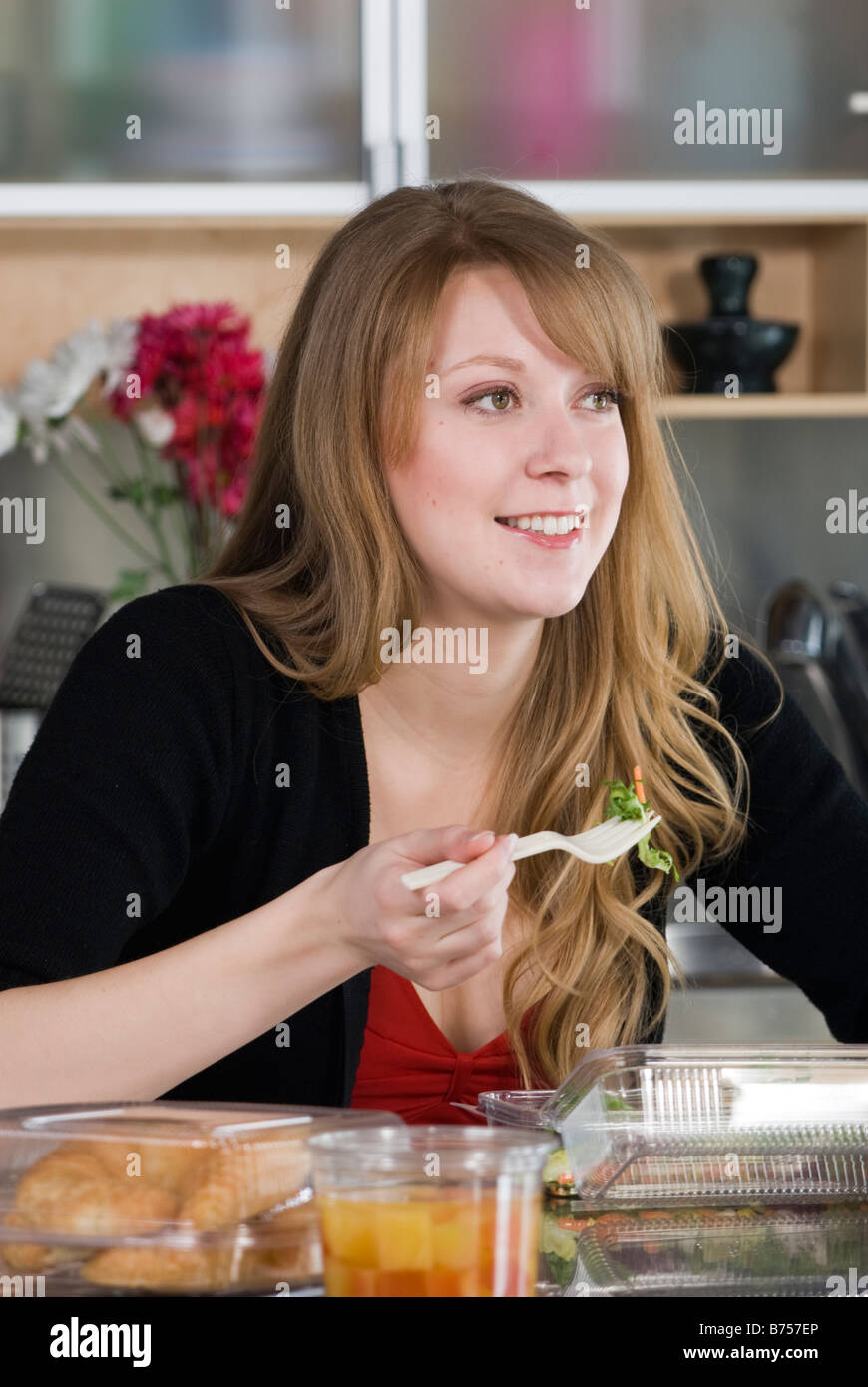 Woman eating take out food from containers and fork made from corn, and ...